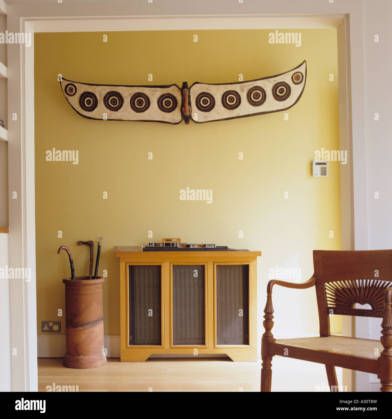 Yellow entrance hall with ethnic wall-piece and umbrella stand Stock ...
