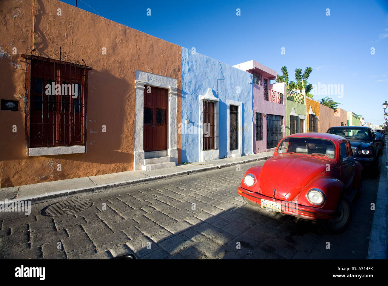 Red Volkswagen Beetle and coloured Spanish Colonial buildings in ...
