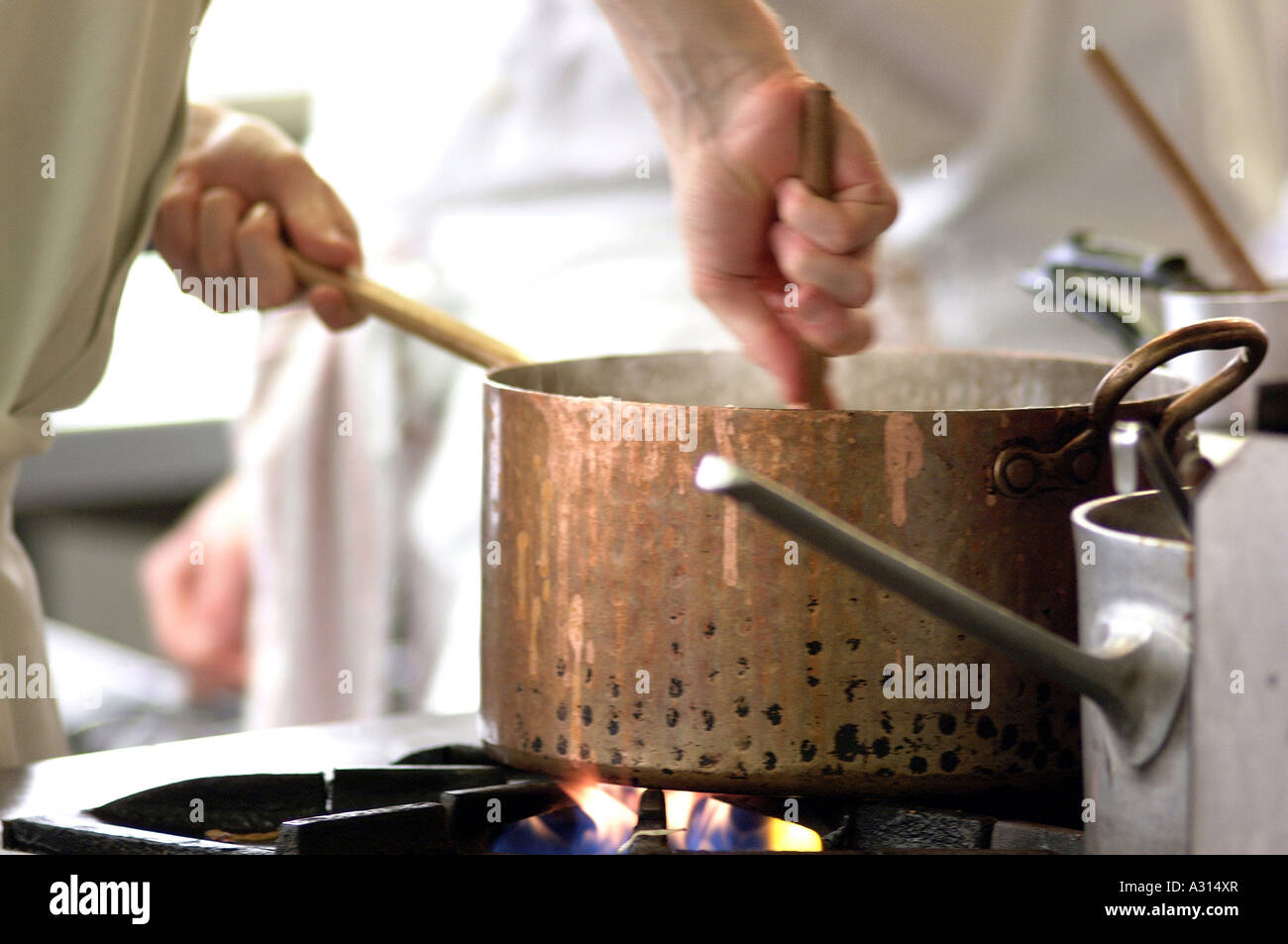 Royalty free photograph of chef cooking on stove stirring a copper pot ...