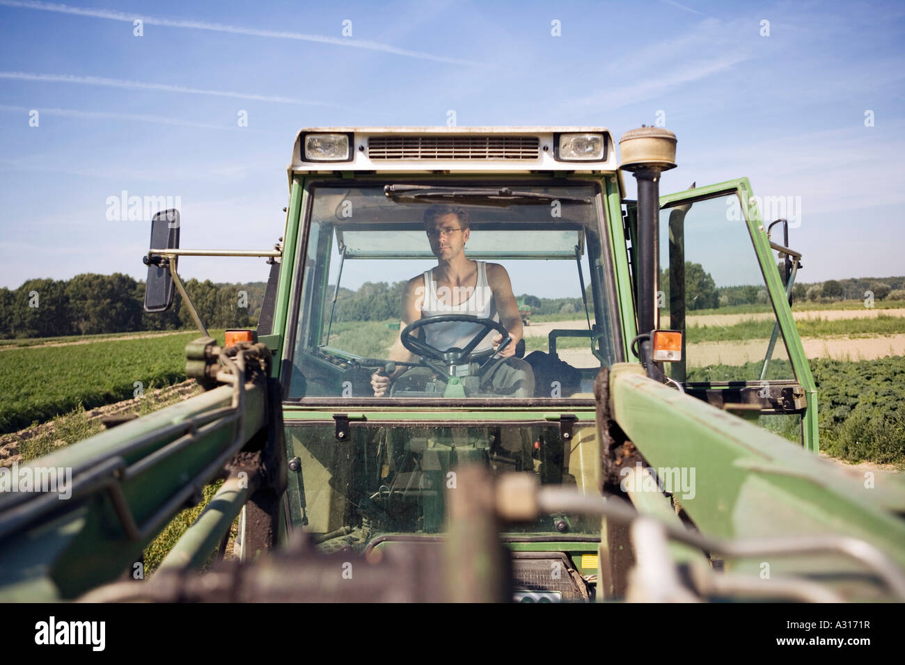 Farmer driving tractor in field Stock Photo - Alamy