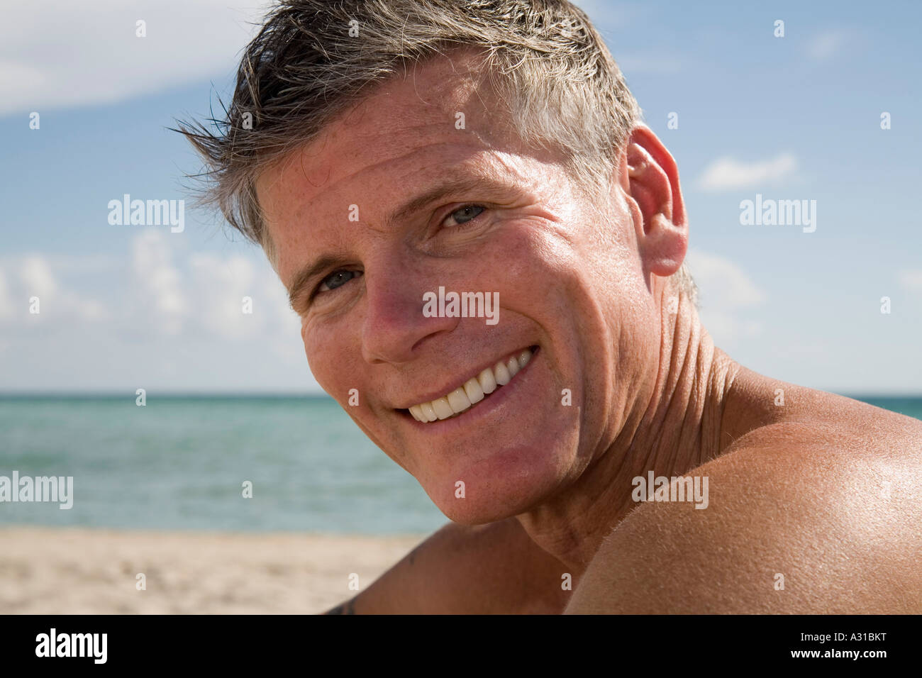 Man sitting on the beach and smiling Stock Photo - Alamy