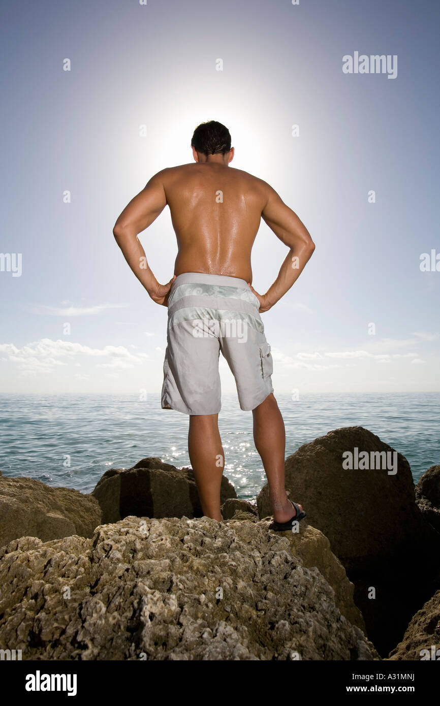 Rear view of man standing on rock in front of sea Stock Photo - Alamy
