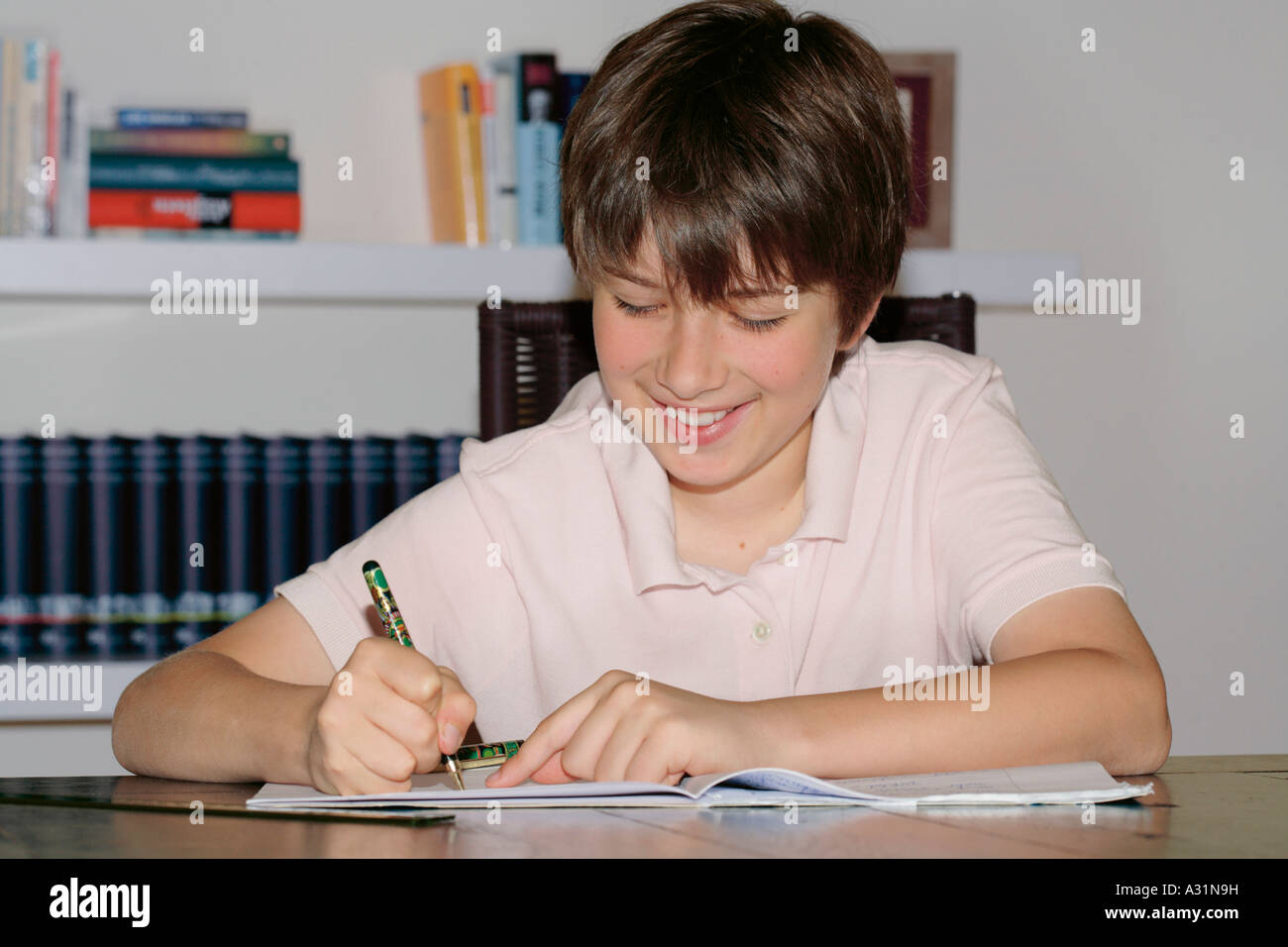 Boy sitting at table doing homework Stock Photo - Alamy