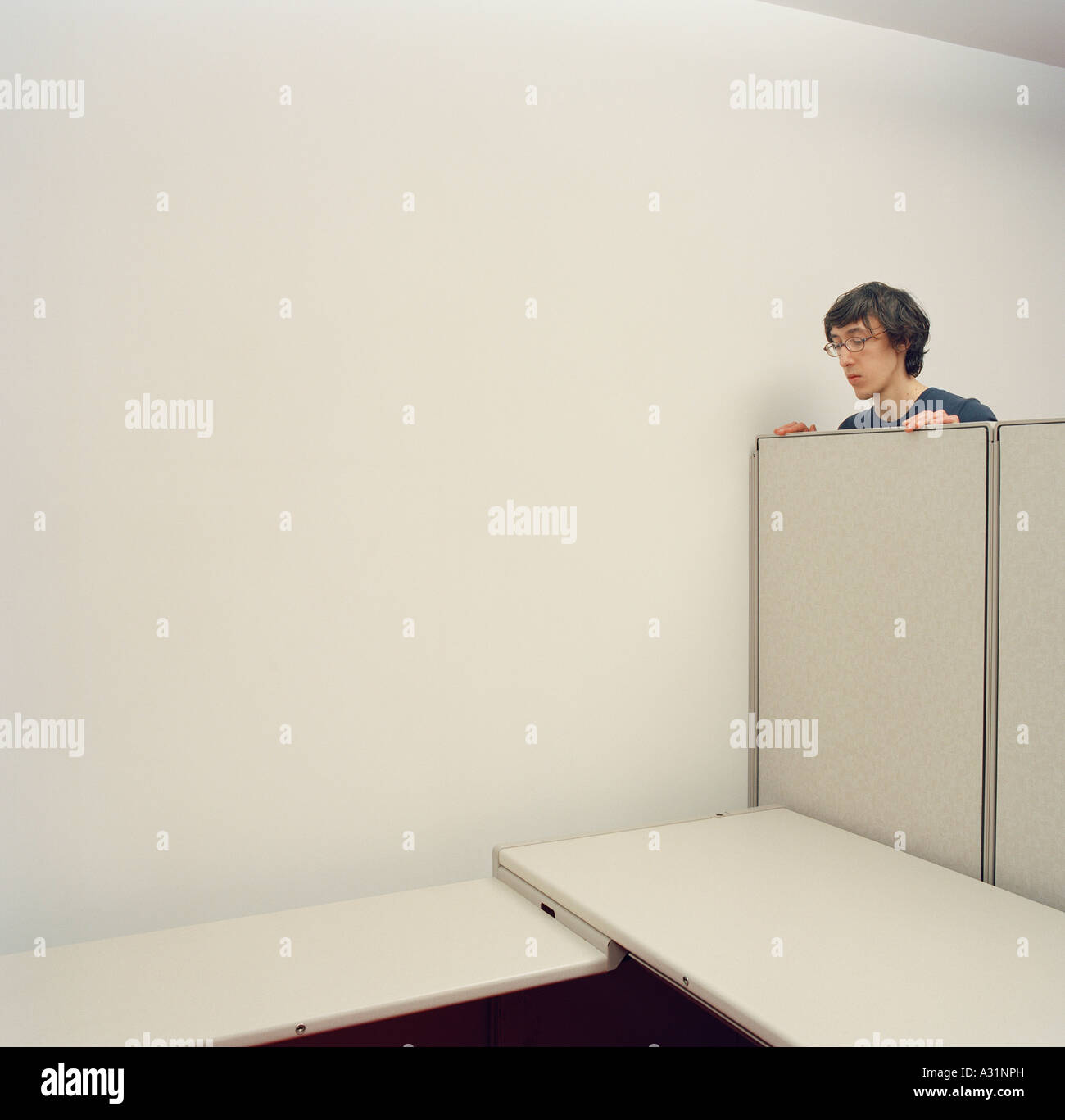 Young man looking over partition wall in empty cubicle Stock Photo - Alamy