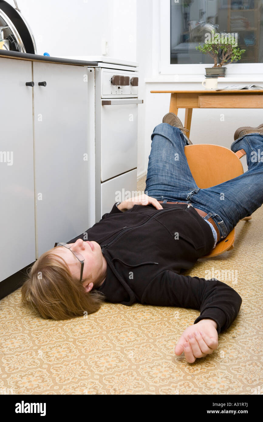 Young man lying on the ground after falling back in a chair Stock Photo ...