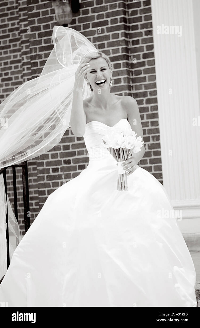 Bride standing on steps with veil blowing in the wind Stock Photo - Alamy