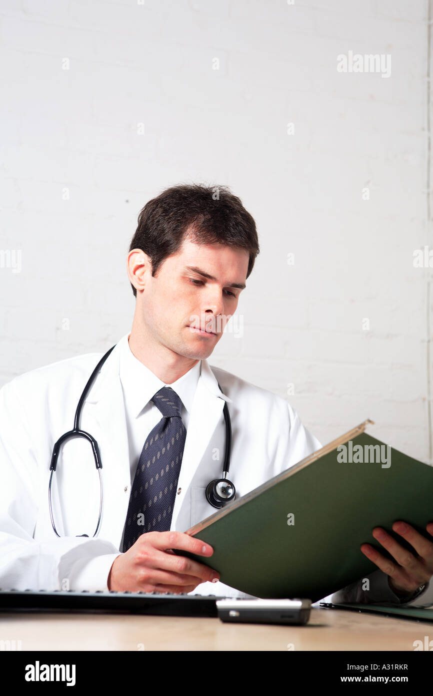 Doctor at office desk looking at files Stock Photo - Alamy