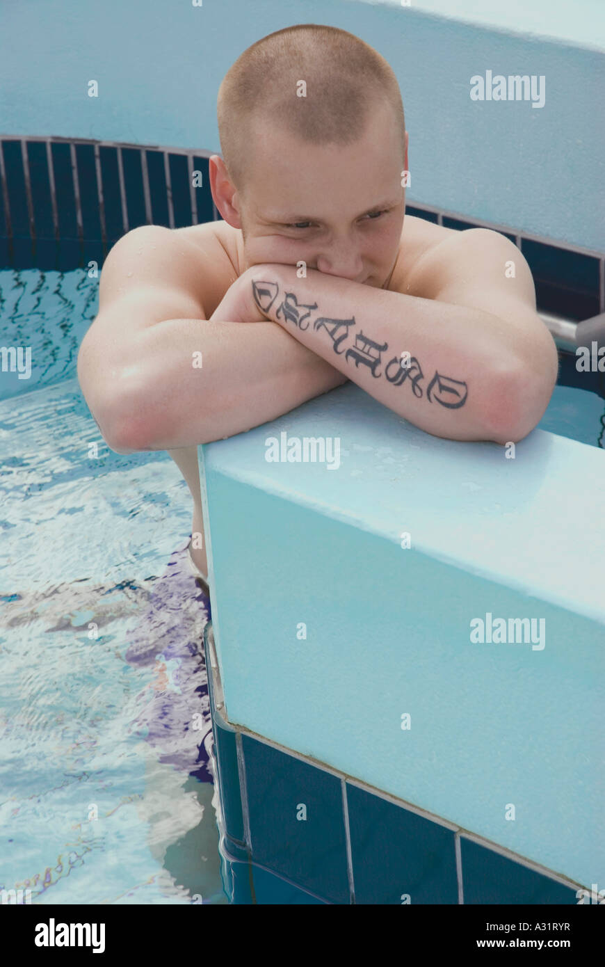 Young man leaning against the edge of a swimming pool Stock Photo - Alamy