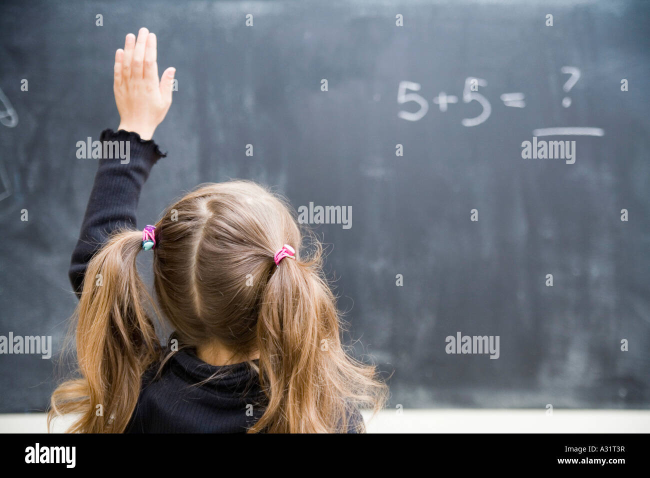 Girl in classroom with raised hand Stock Photo - Alamy