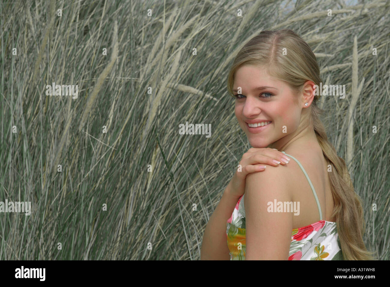 Young woman in field looking over shoulder smiling Stock Photo - Alamy