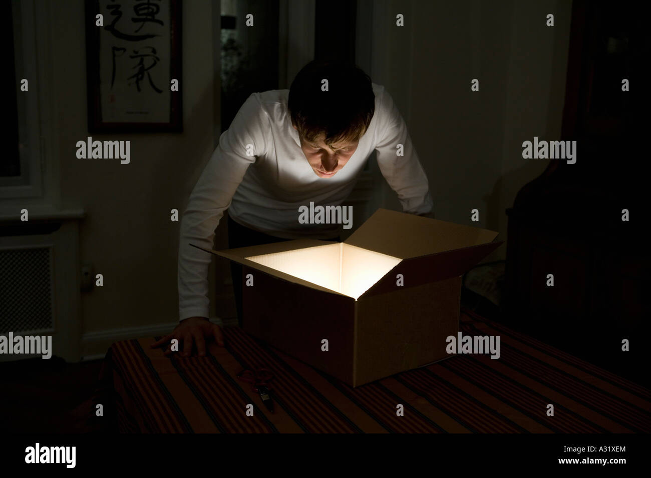 Young man staring into illuminated cardboard box Stock Photo - Alamy