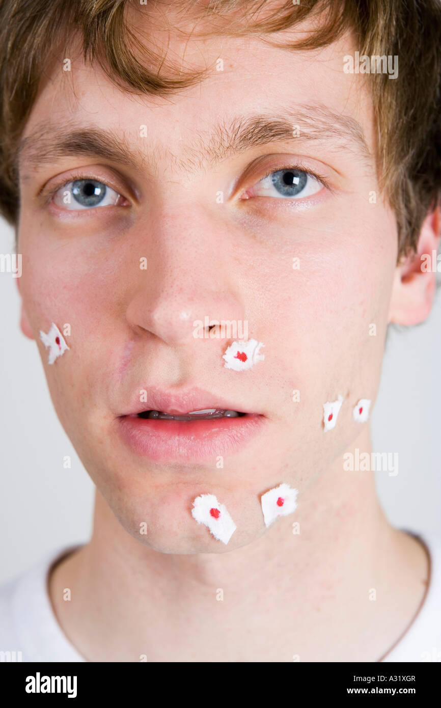 Young man with tissue paper on shaving wounds Stock Photo - Alamy