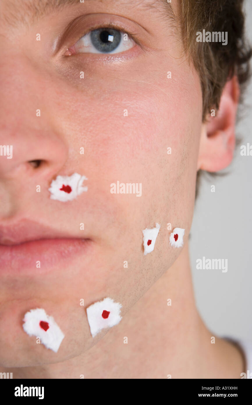 Young man with tissue paper on shaving wounds Stock Photo - Alamy