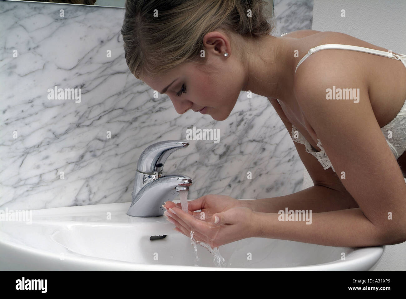 Young woman with hands cupped under running tap Stock Photo - Alamy