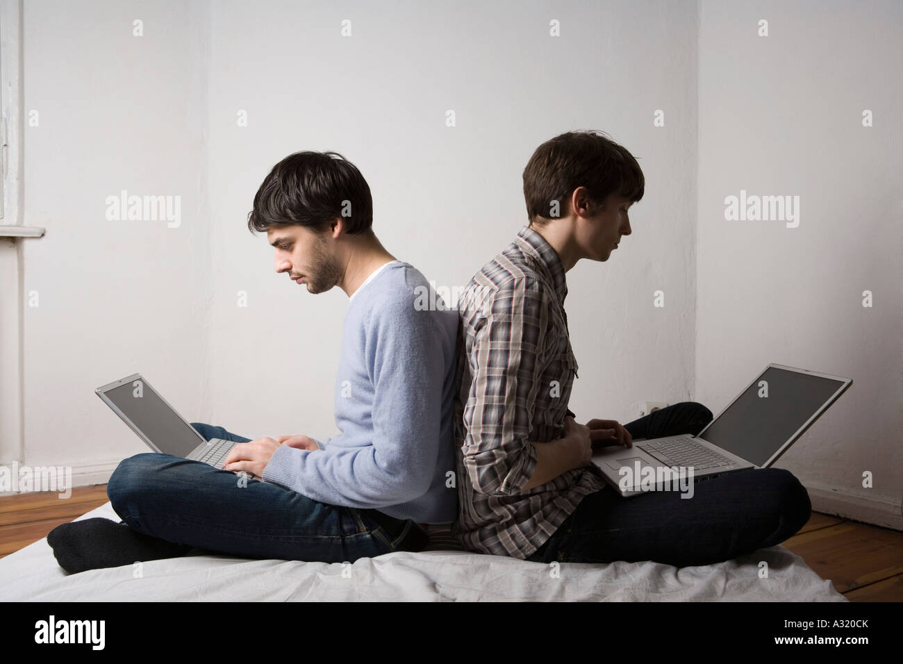 Two young men sitting back to back using laptops Stock Photo - Alamy Two young men sitting back to back using laptops Stock Photo - Alamy