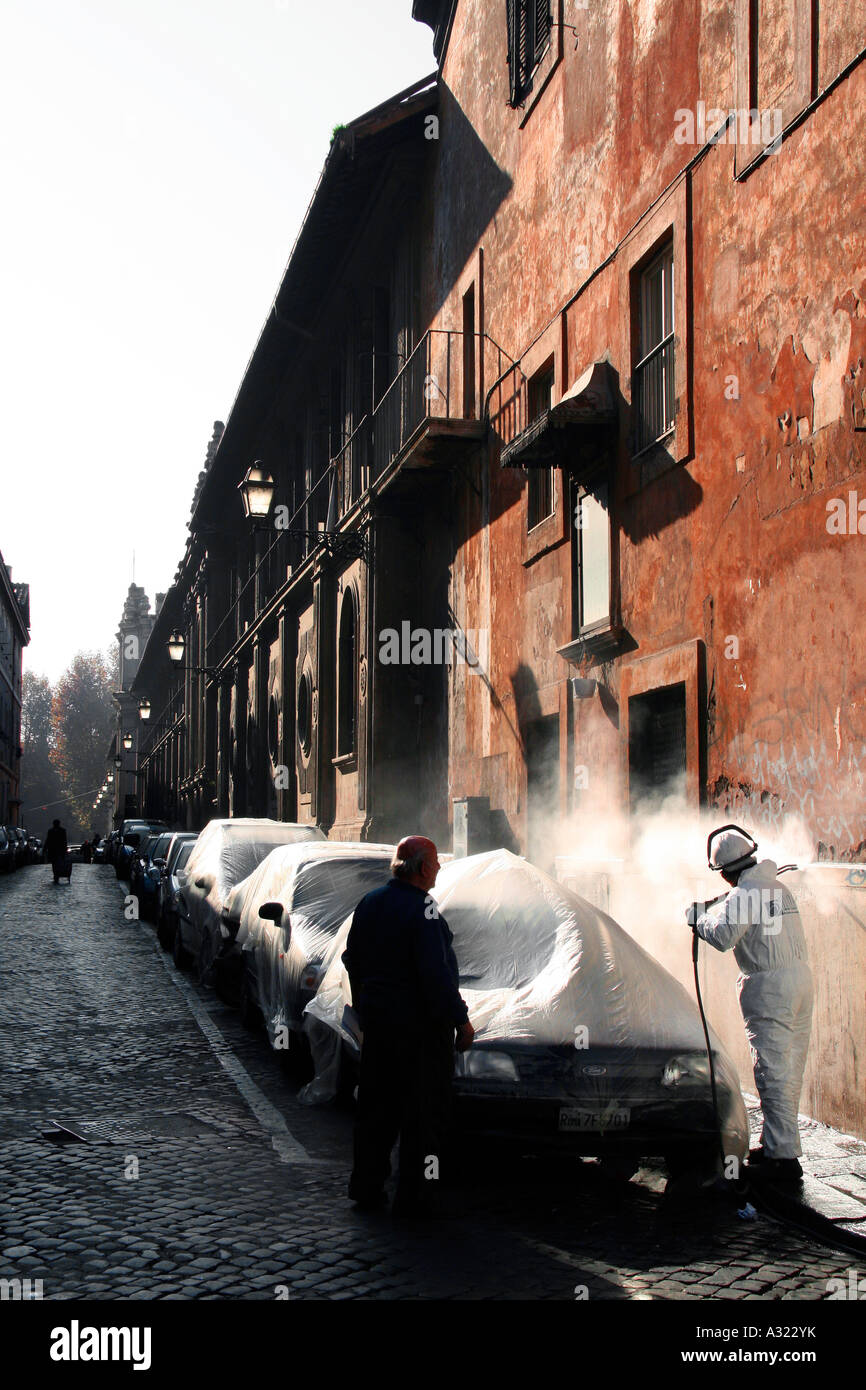 Man pressure spraying to remove graffiti in the Trastevere area of Rome ...