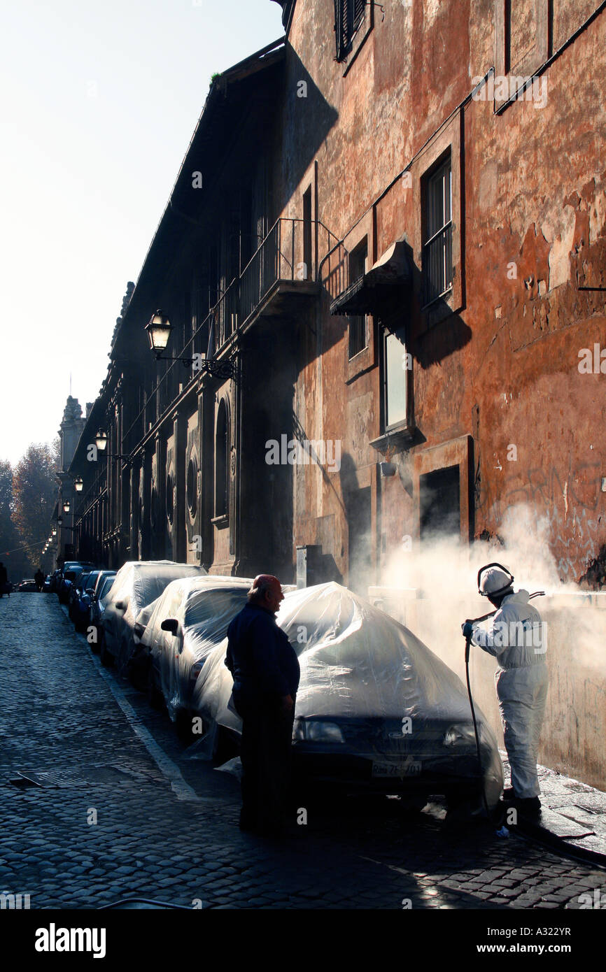 Man pressure spraying to remove graffiti in the Trastevere area of Rome ...