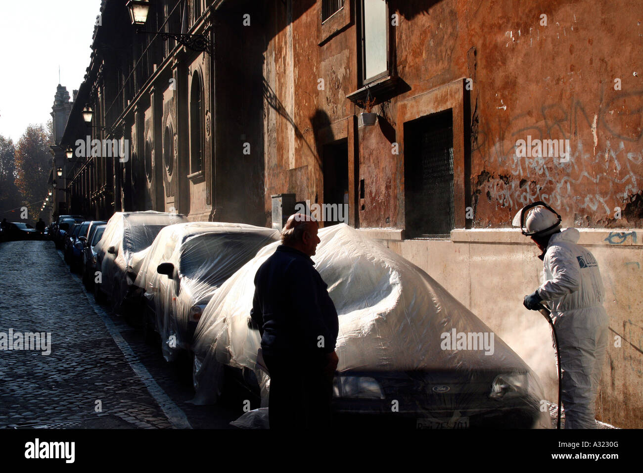 Man pressure spraying to remove graffiti in the Trastevere area of Rome ...