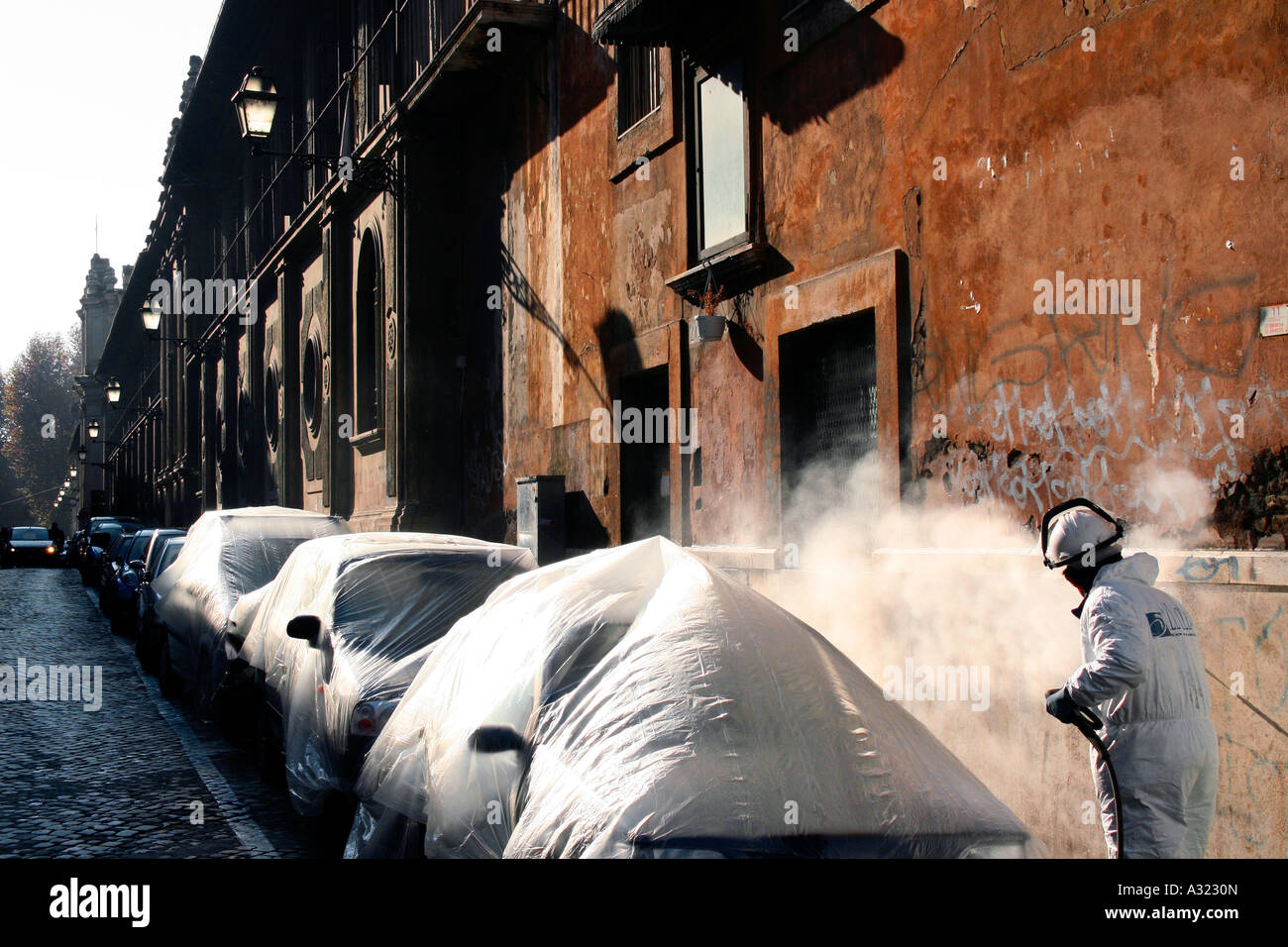 Man pressure spraying to remove graffiti in the Trastevere area of Rome ...