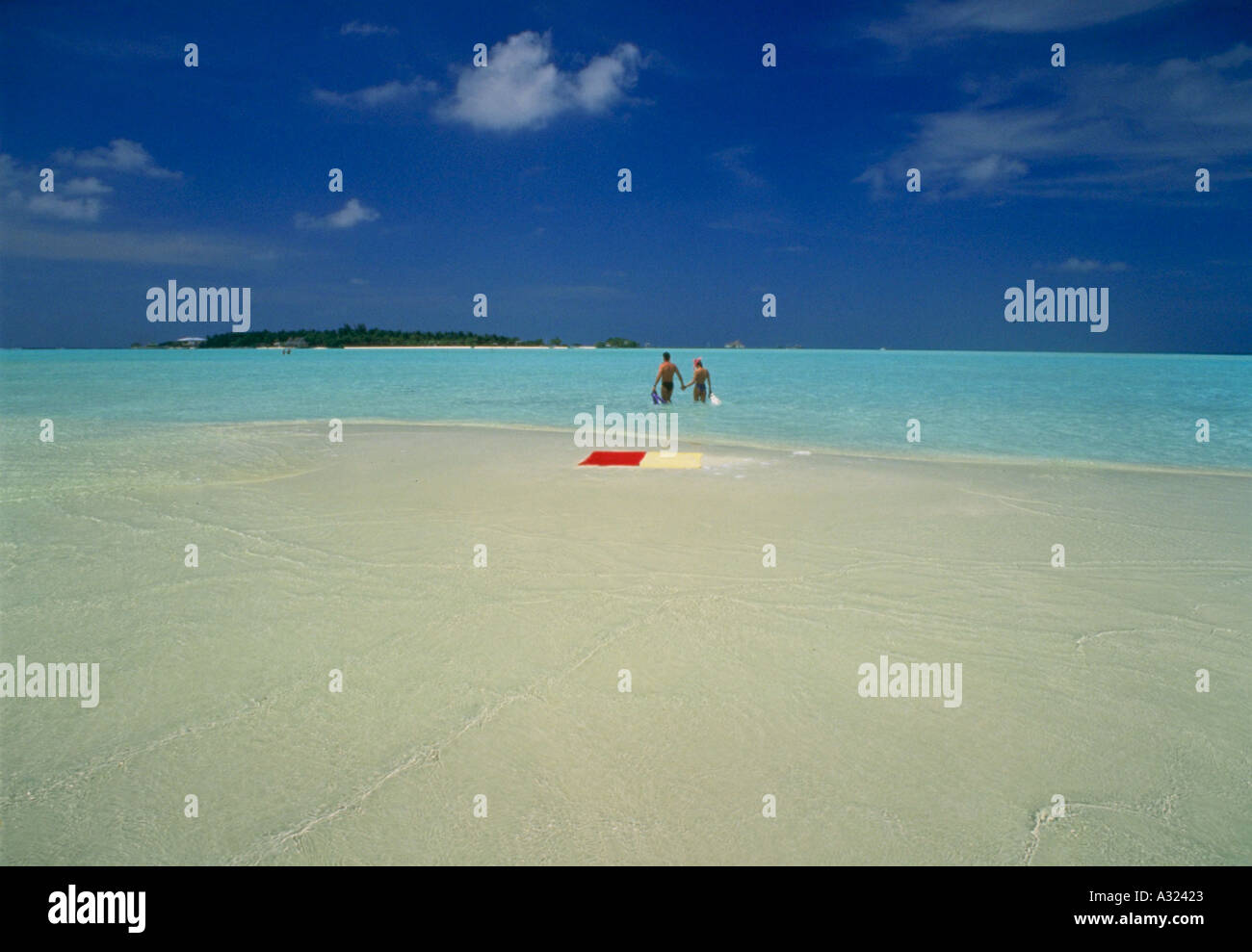 Beach towels on sandbar with couple walking in surf Maldive Islands ...