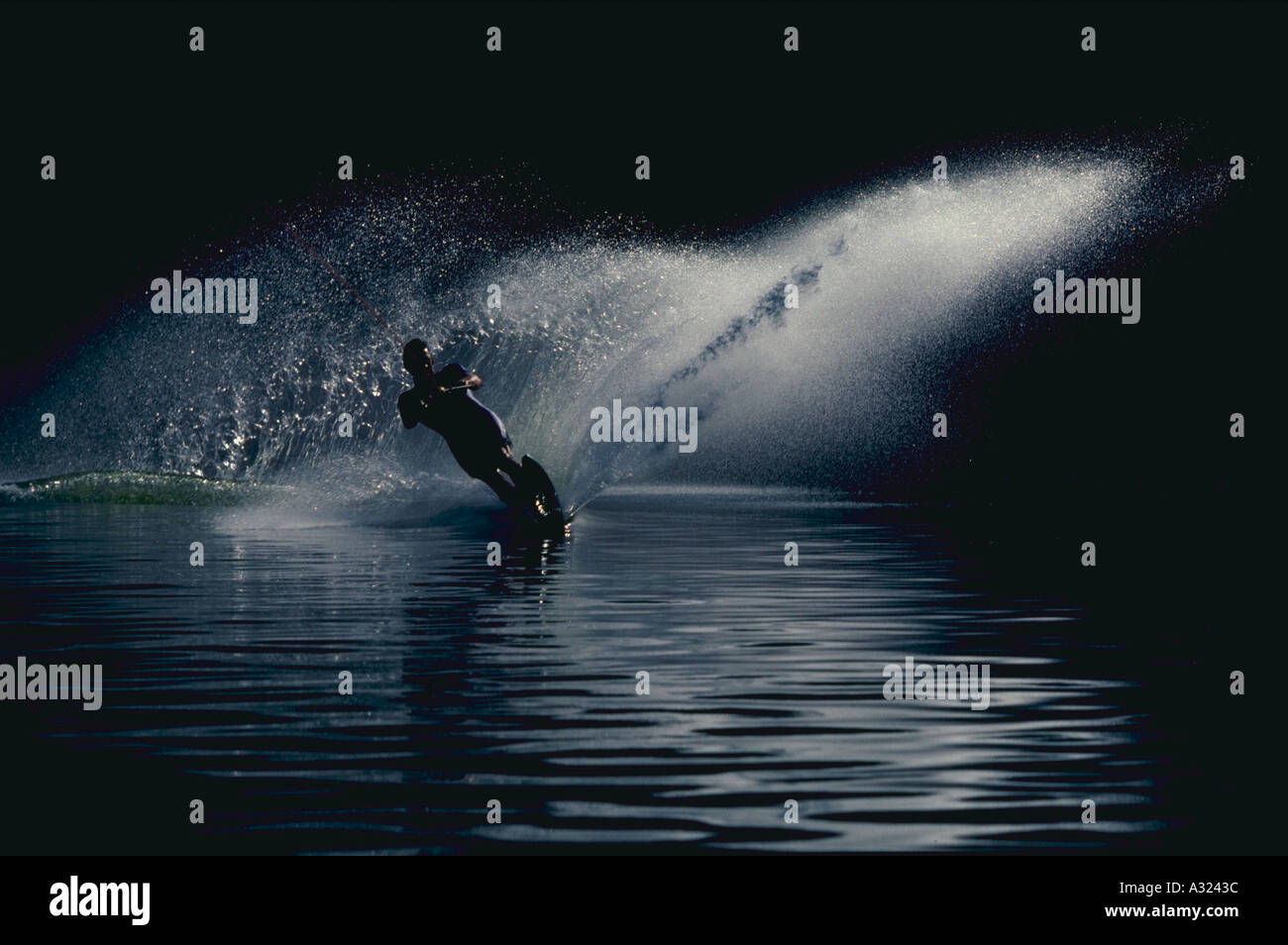 Man water skiing in morning light with spray of water Stock Photo - Alamy