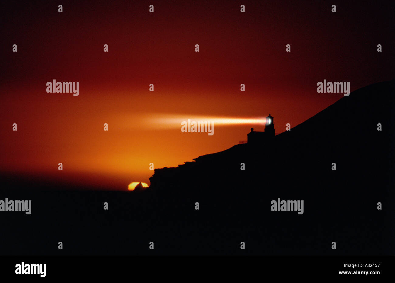 Light beams radiate from Point Conception lighthouse against orange sky ...