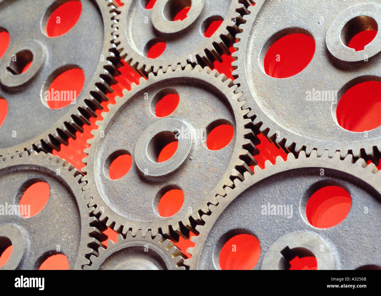 Several gears interlocked laying n a red background Stock Photo - Alamy