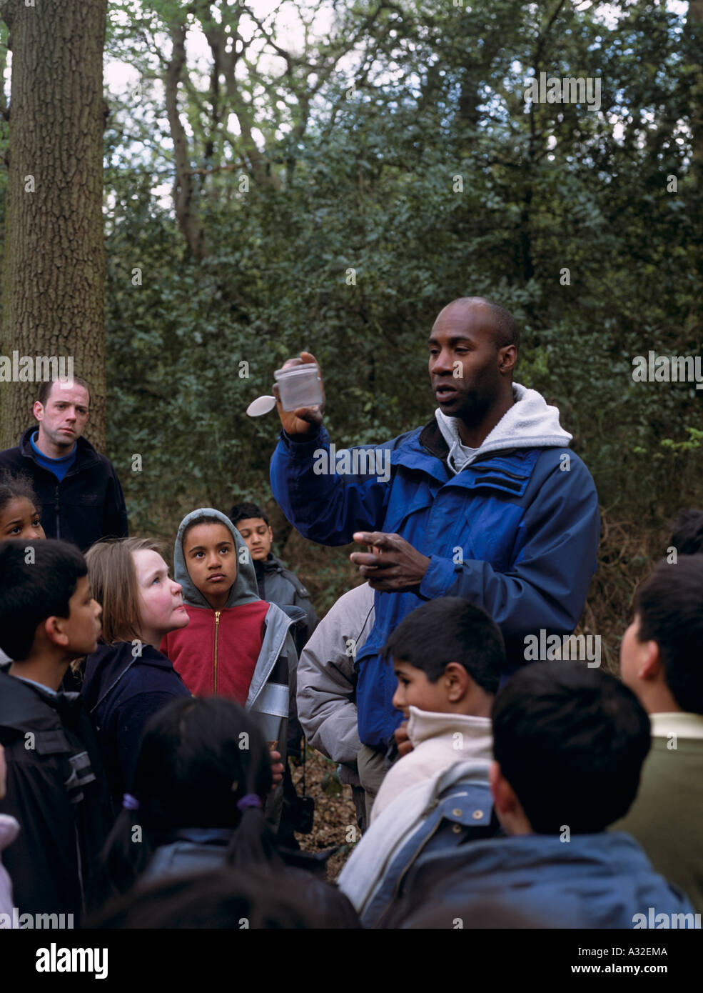 Educationalist explaining nature with children in Spring woodland ...