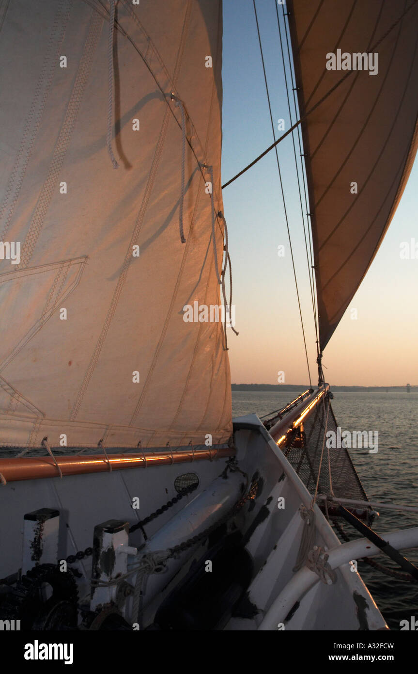 The bow of a schooner with sails sailing towards the sunset Stock Photo ...