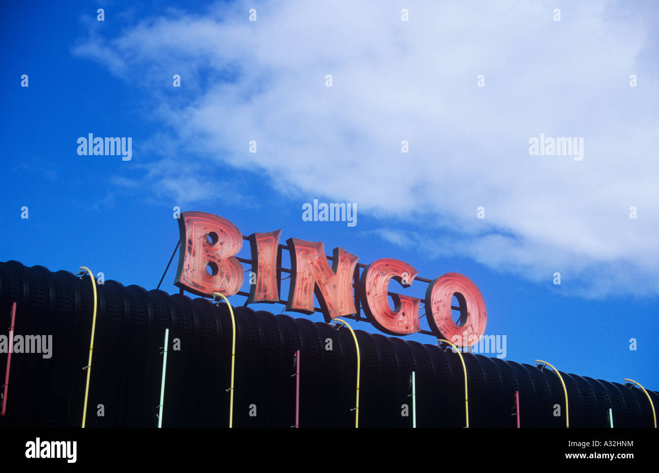 Red neon sign stating Bingo on black plastic roof with coloured strip ...