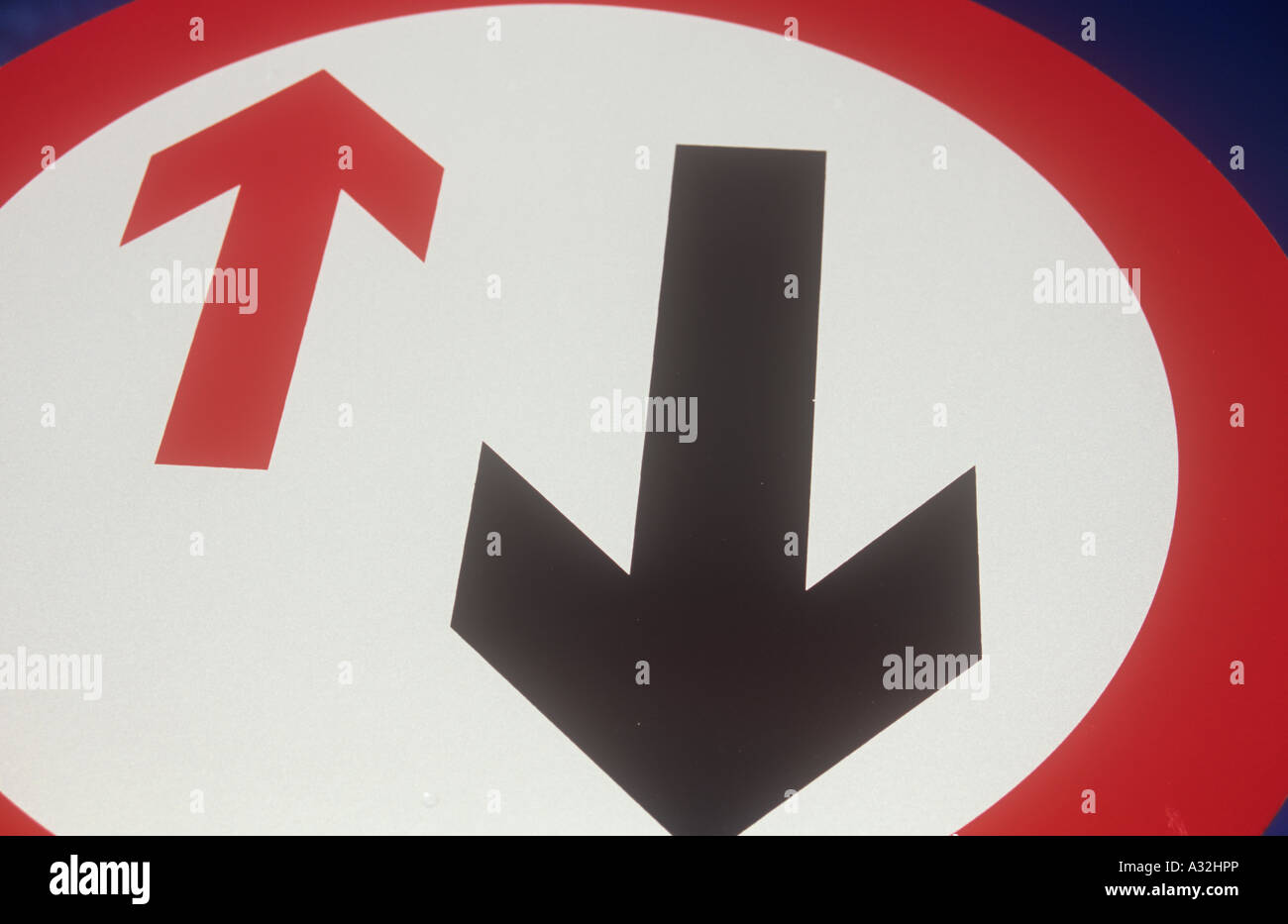 Circular red and white sign with black and red arrows against blue sky ...