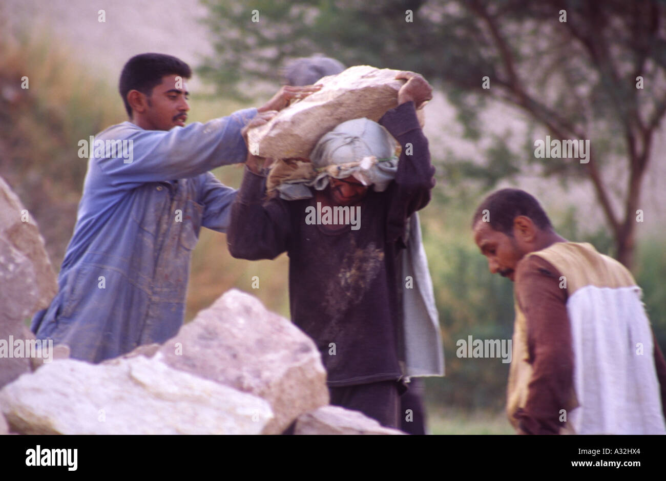 Egyptian labourers carry heavy rocks on their heads onto a barge, Egypt ...