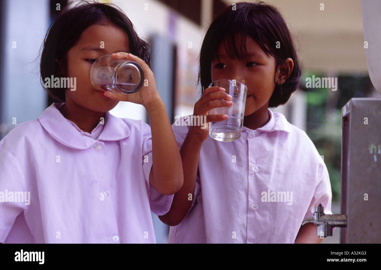 Two schoolgirls in uniform drink fresh water provided at their school ...