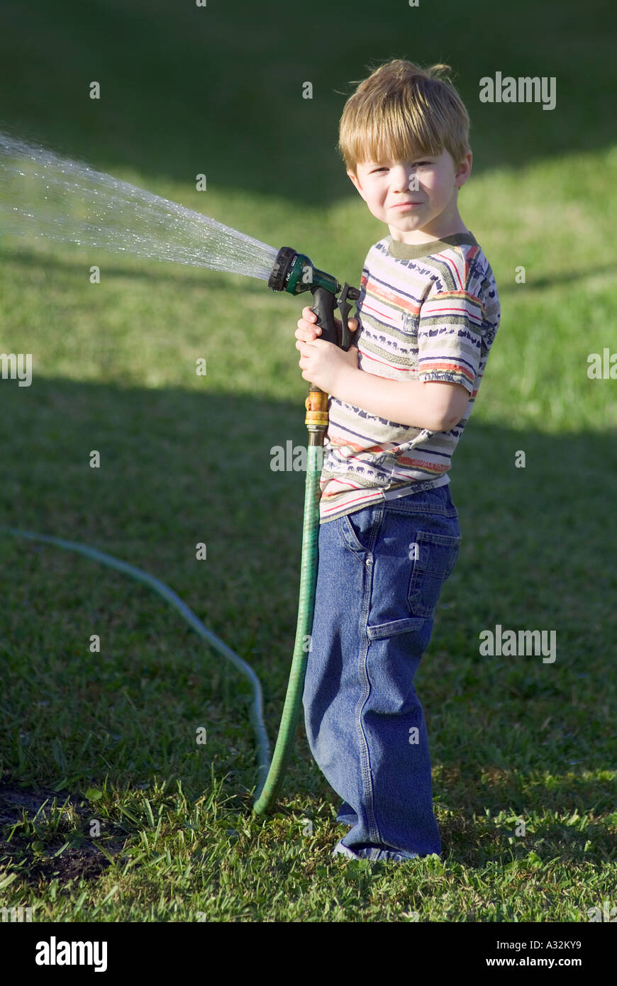 child watering tree grass yard work outdoors helper helping hose water ...