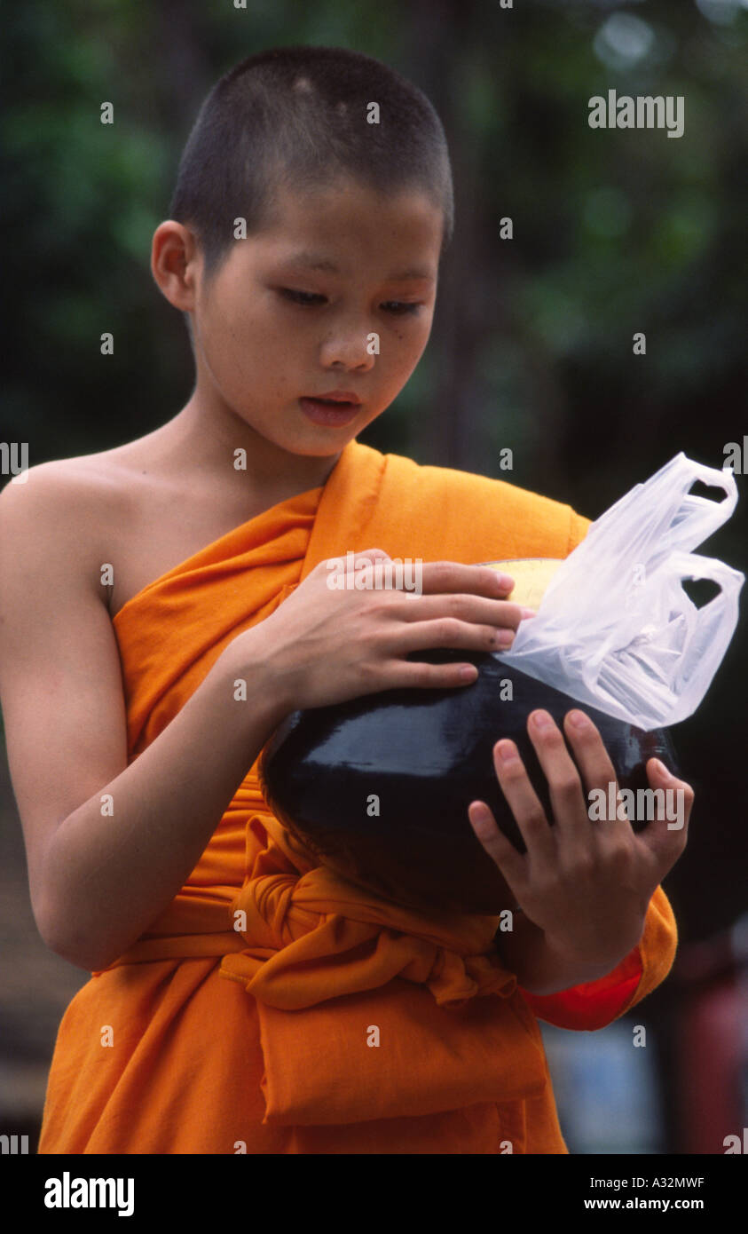 Vertical portrait of young Thai boy collecting alms as a novice ...