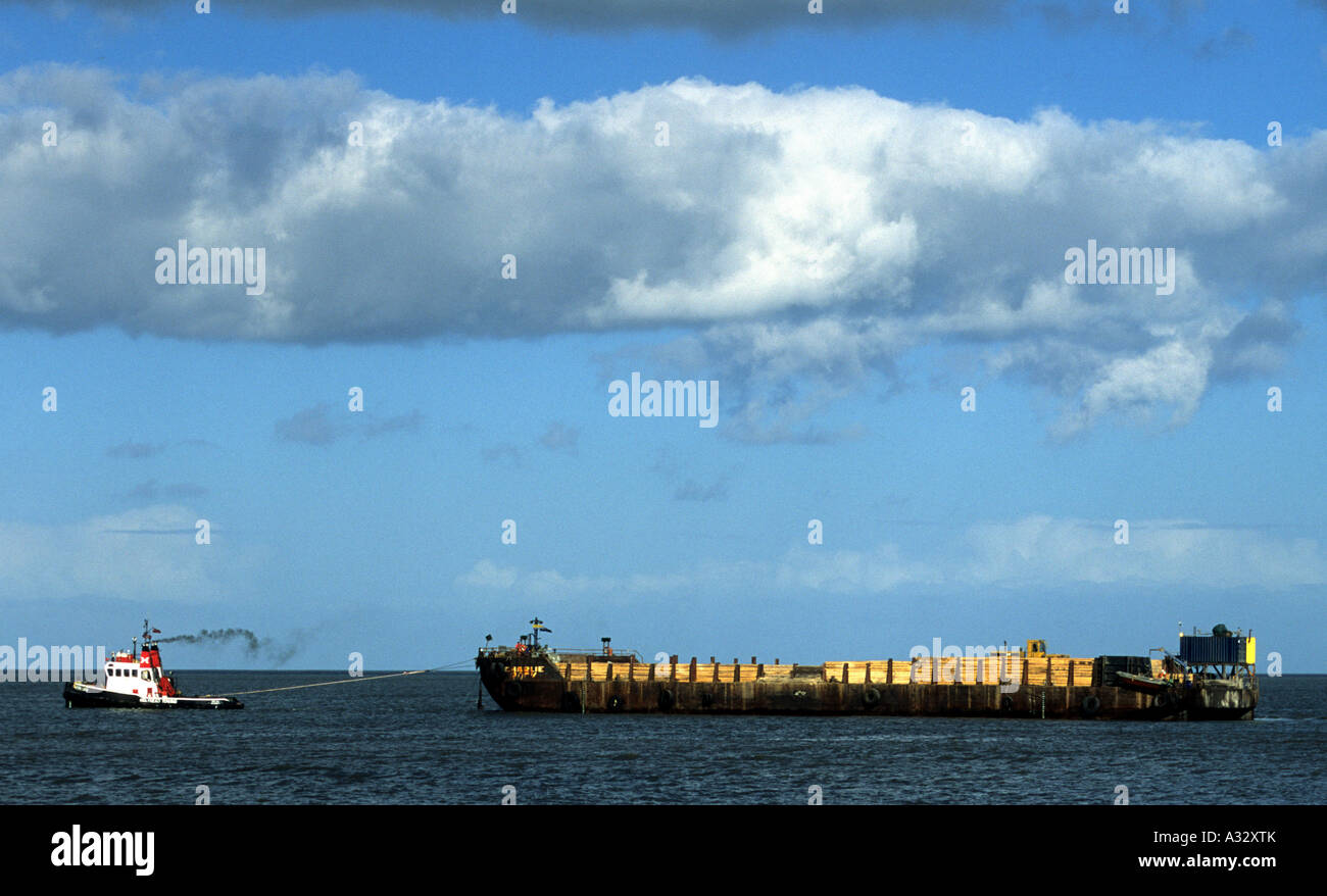 Tug boat towing a barge loaded with rocks for coastal defences ...