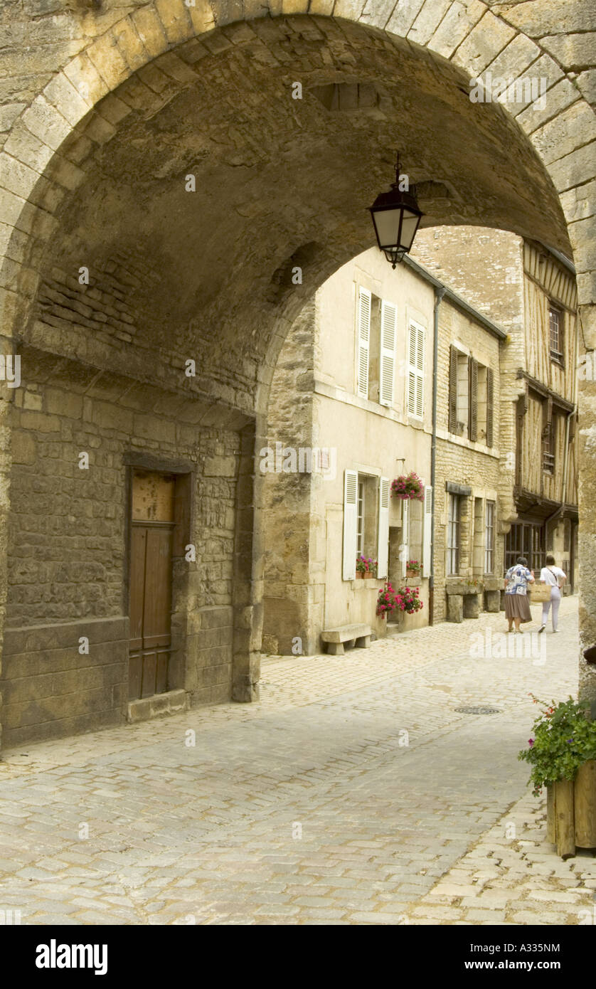 Cobblestone street through the entrance gate to the village of Noyers ...