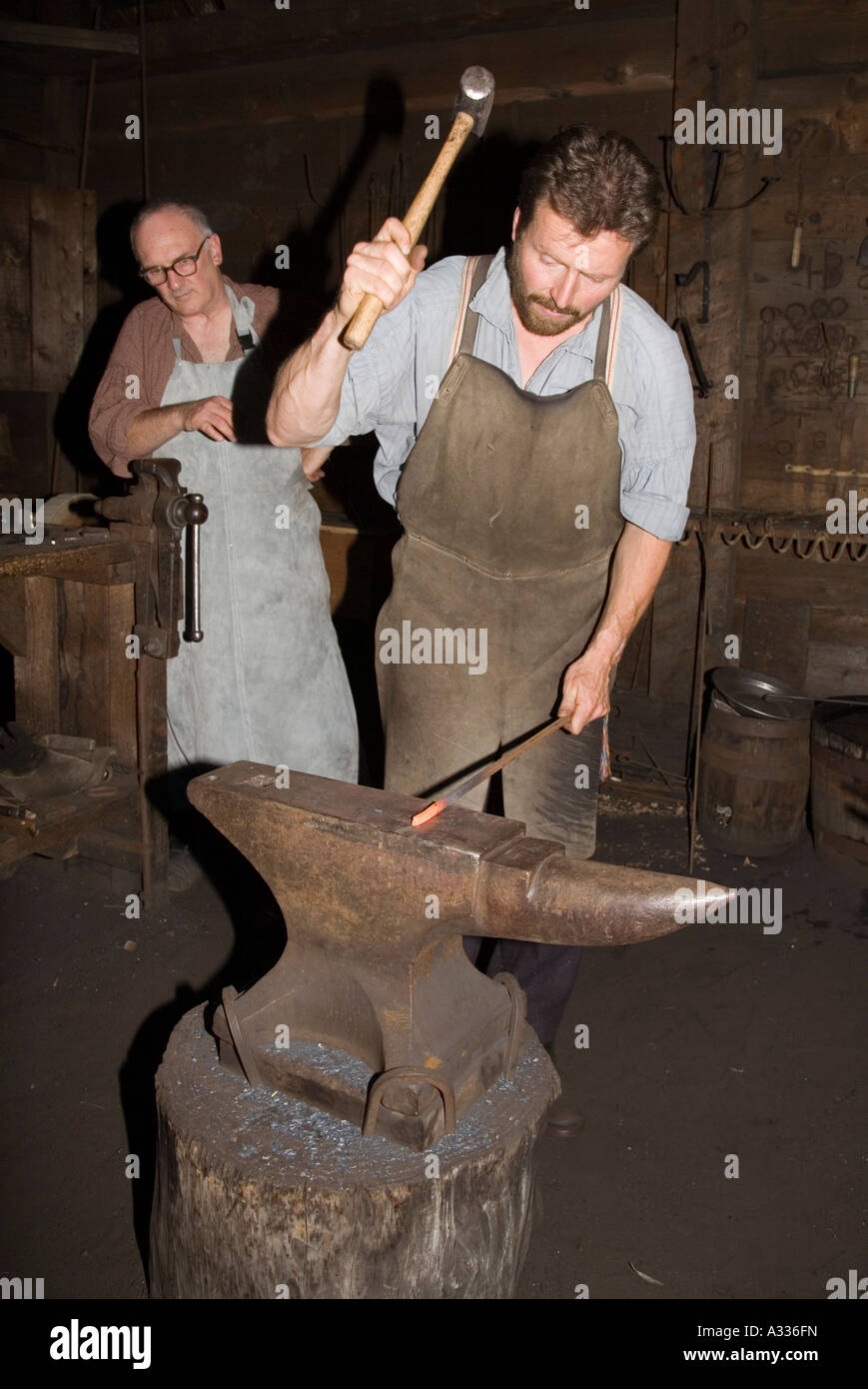 Blacksmith working at anvil teaching another man at Fort Langley ...
