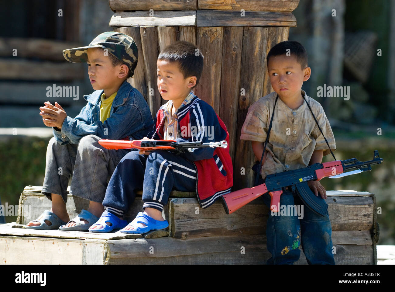 Mischievous boys play with toy plastic rifles in village square of ...