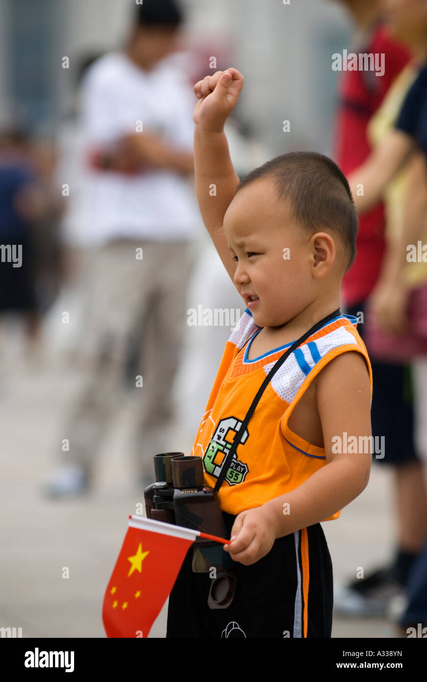 Posing for parent's snap shot, young boy salutes and holds Chinese flag ...