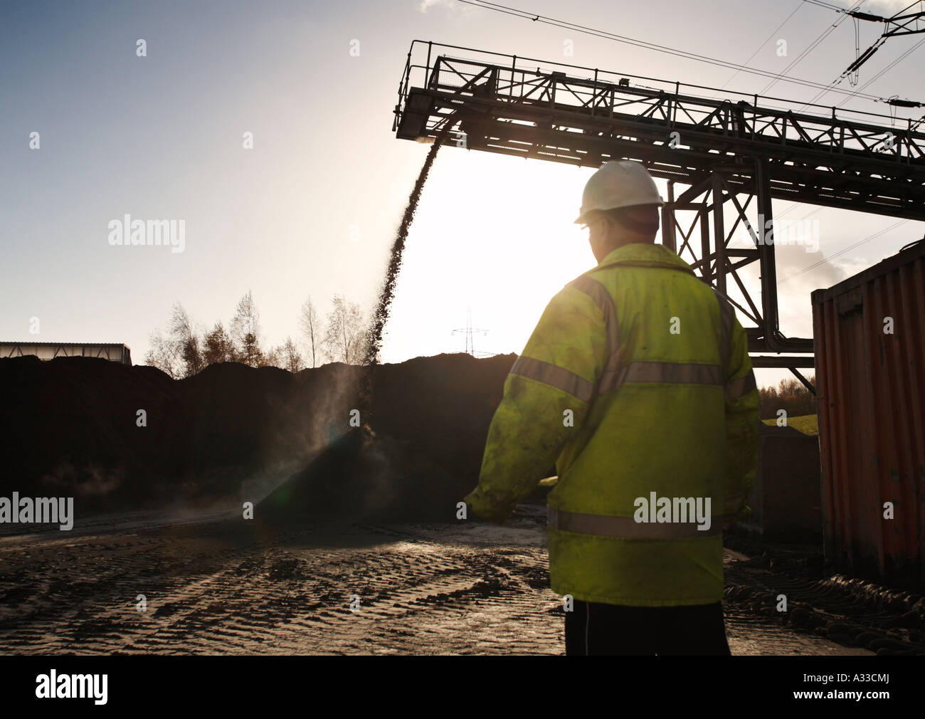 Worker watches a conveyor belt delivering waste washed ash for disposal ...