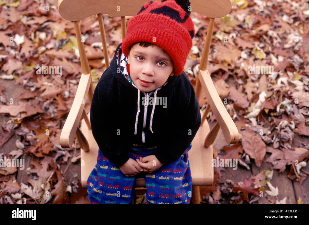 Young boy sitting in rocking chair surrounded by Autumn leaves Stock ...