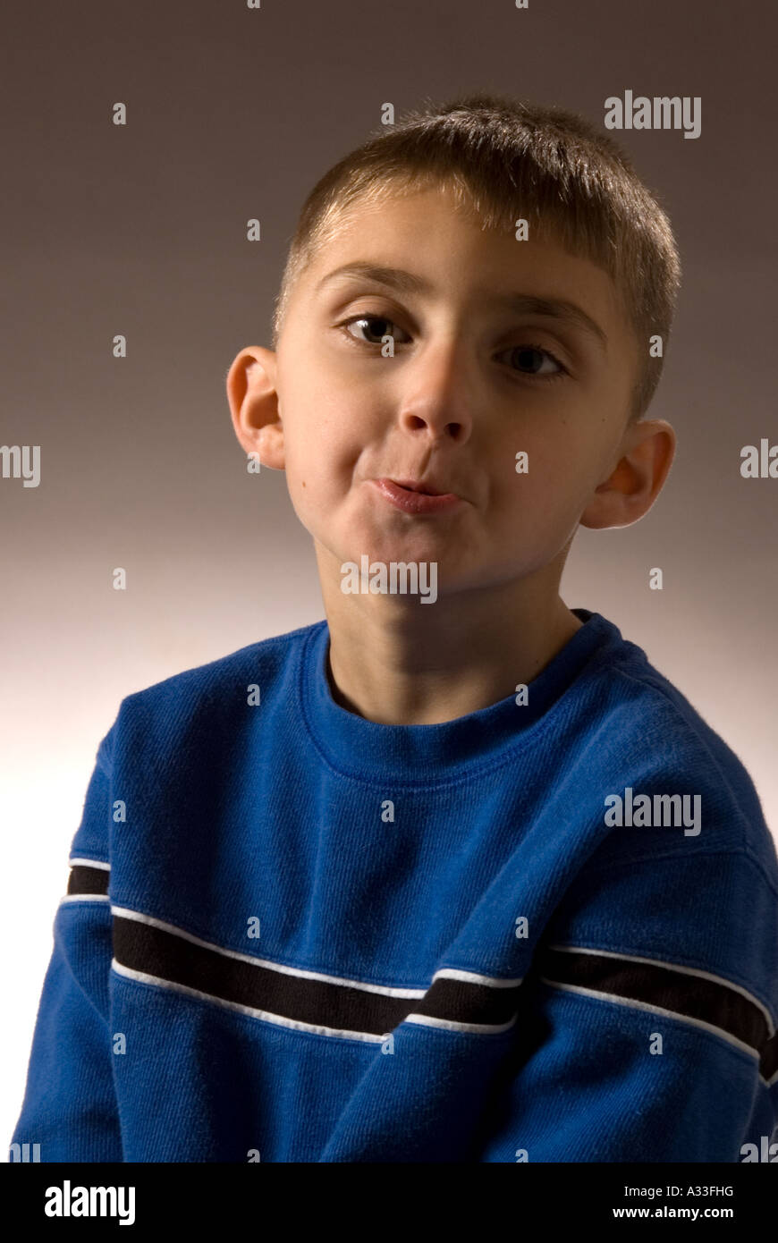 Formal portrait setting of a young boy making faces for the camera ...