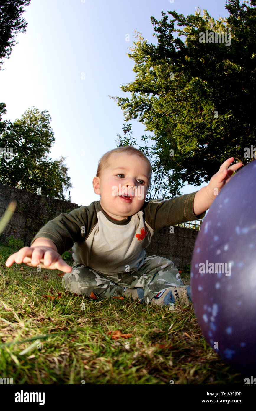 toddler crawling after a football in the garden happy playing shoot low ...