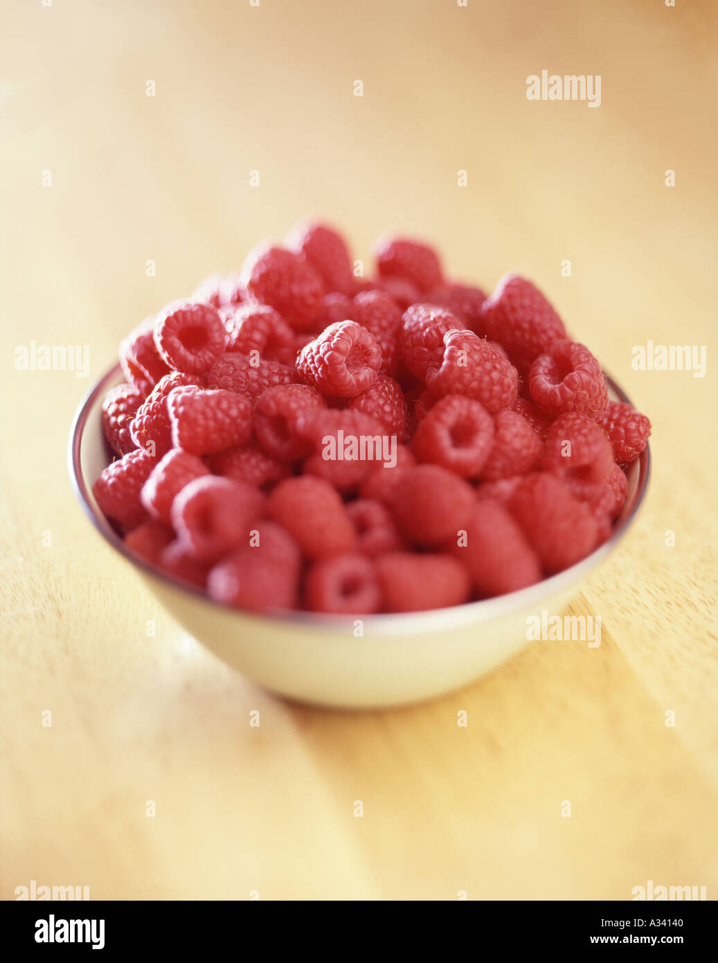 Berries Berry Red Raspberries in a bowl on light wood background Stock ...