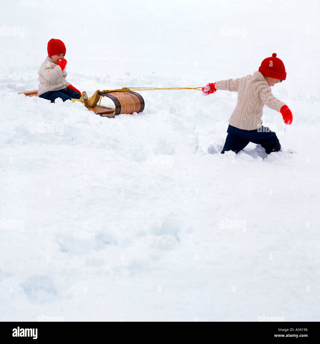 A young child pulling another child on a toboggan type sled through the ...