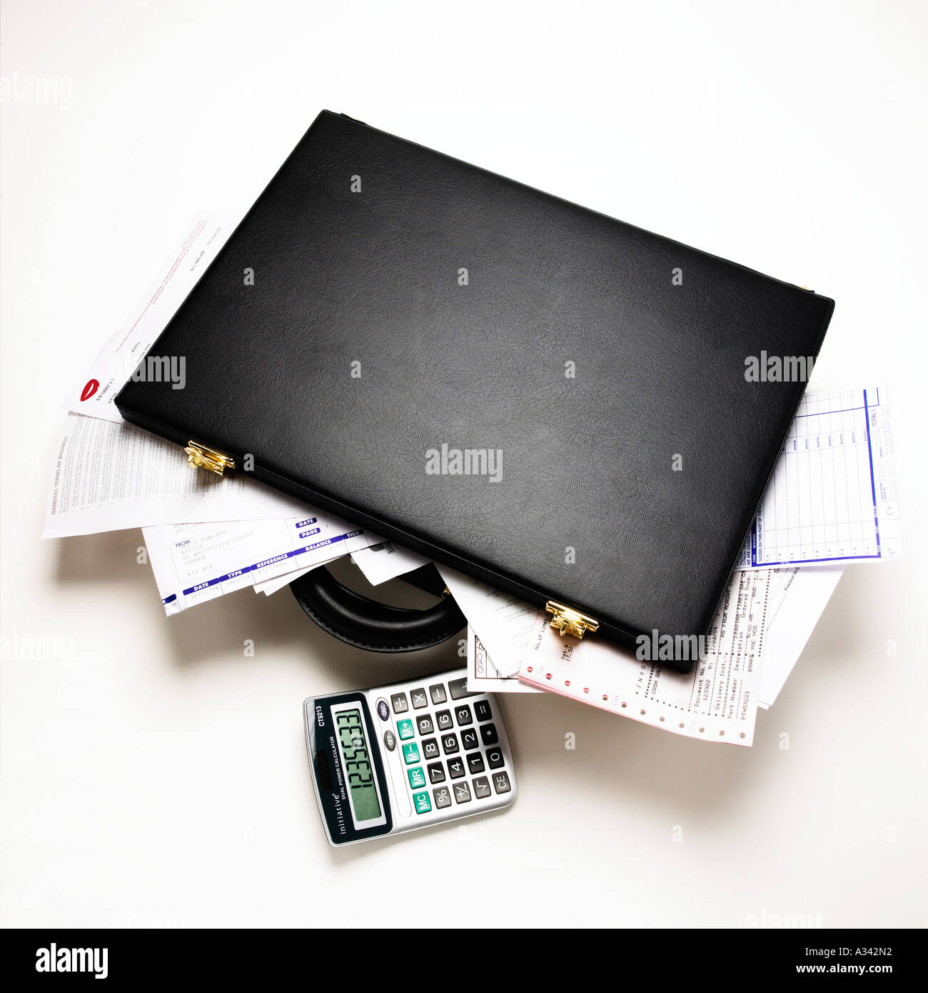 closed black briefcase overflowing with paper bills and a calculator ...
