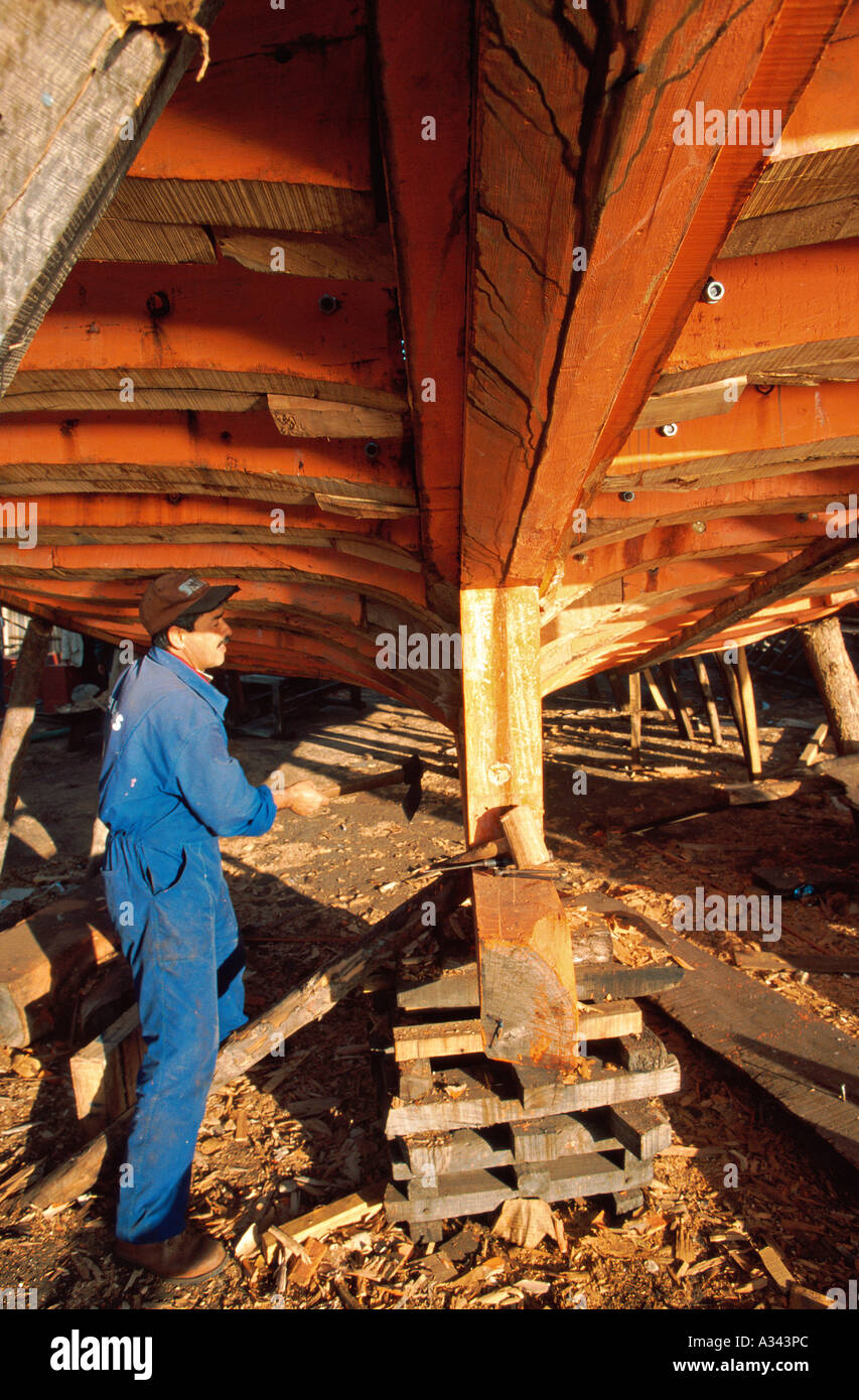 Shipwright under the hull of a trawler in the shipyard of Essaouira ...