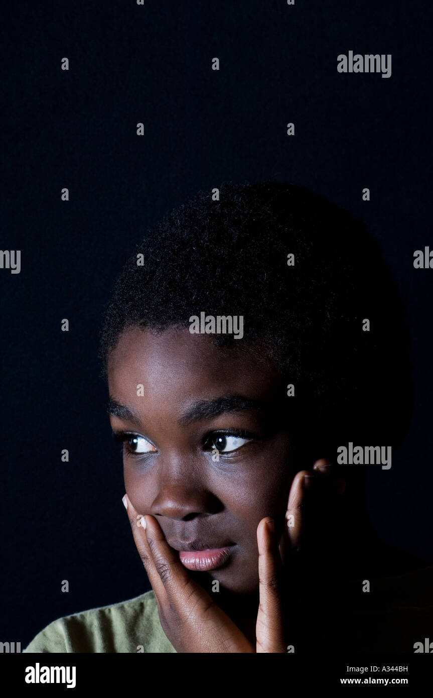 Portrait of a concerned young boy with his hands on his cheeks looking ...