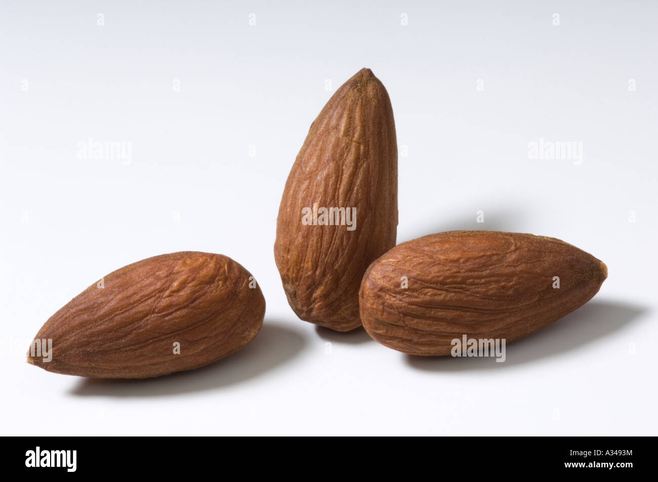 3 three roasted almonds on plain white background Stock Photo - Alamy